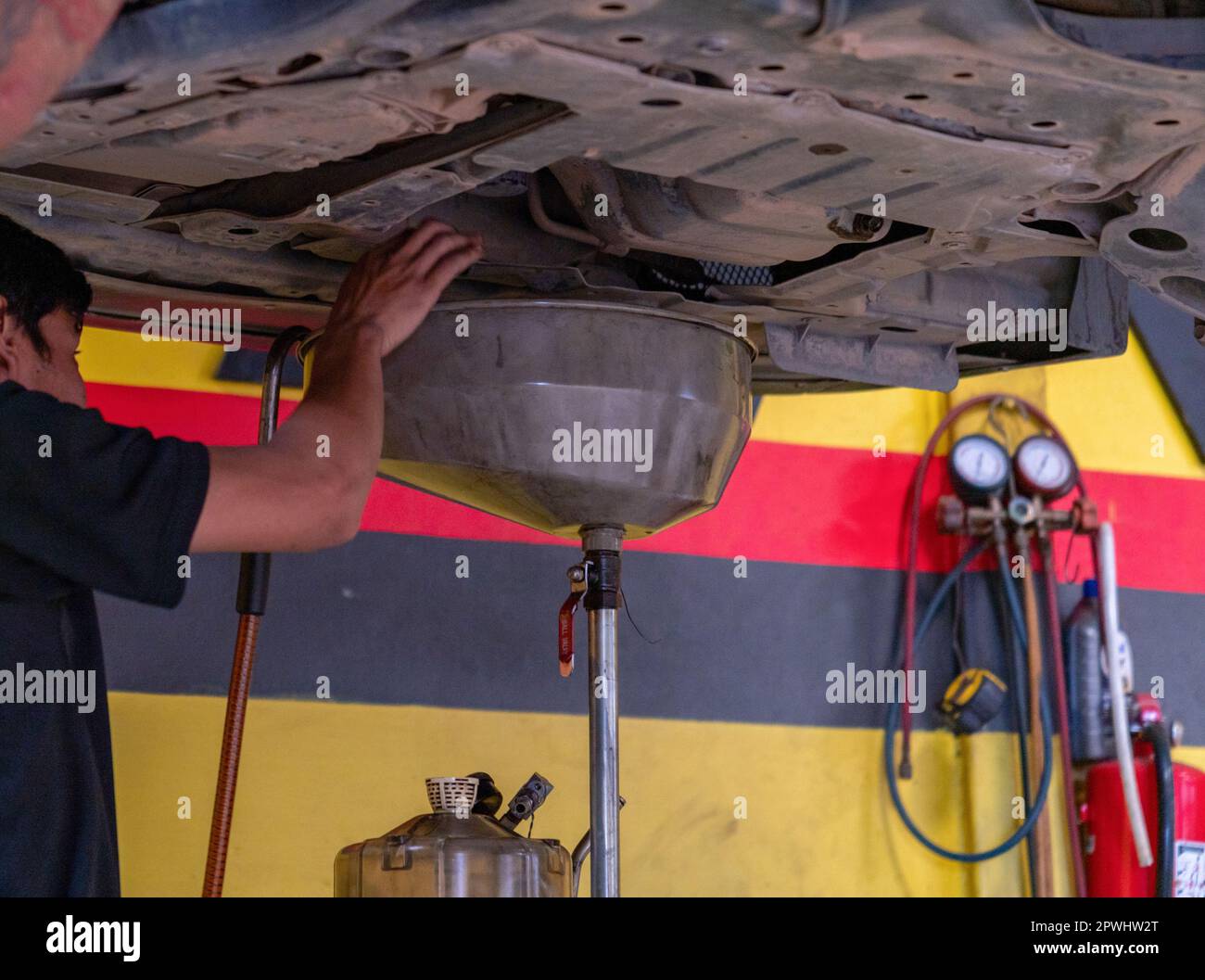 Technician use oil tub under engine for change lubricant car. Energy ...