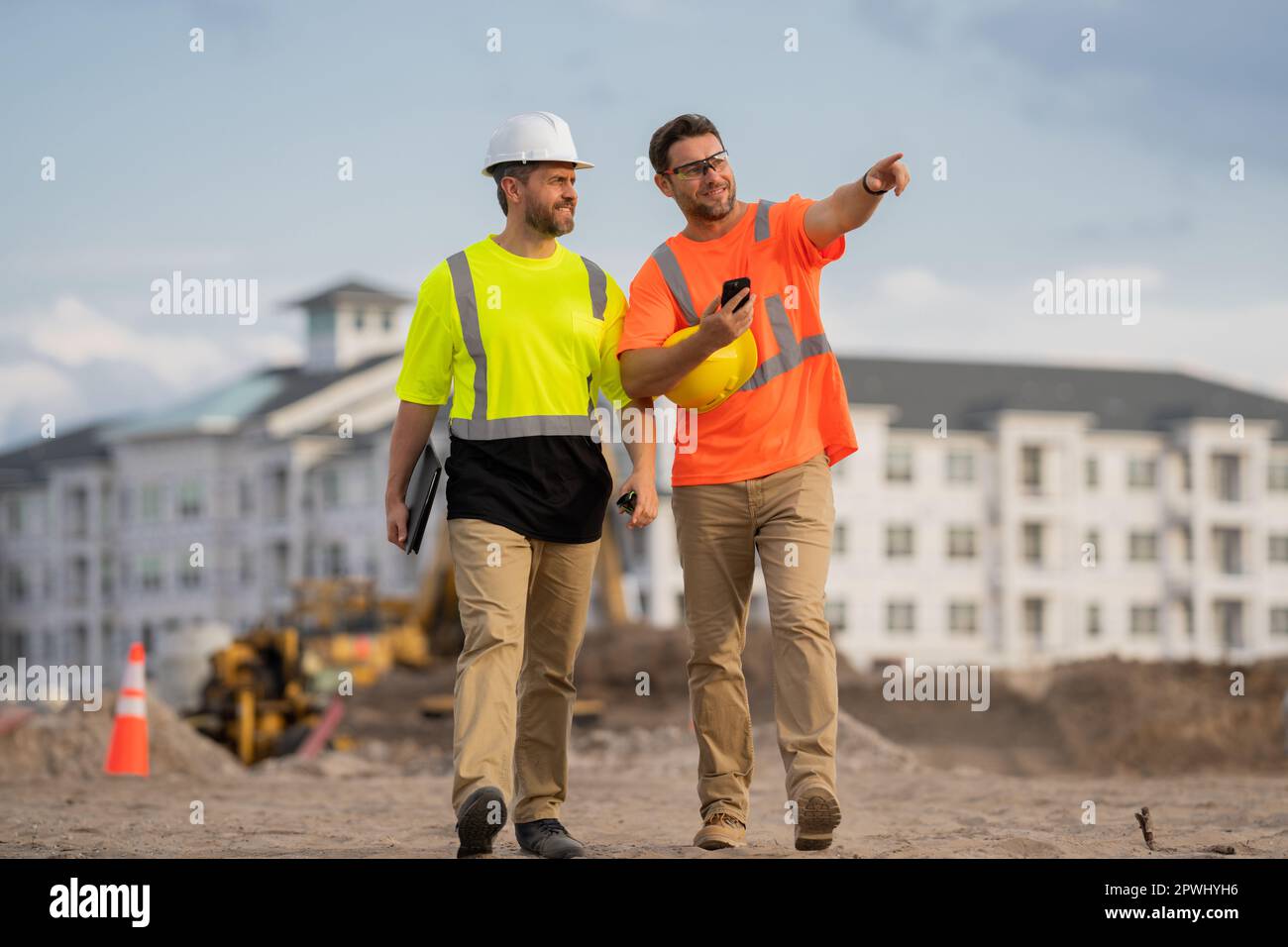 Construction site workers in a helmet work hard. Two workers in a hard ...