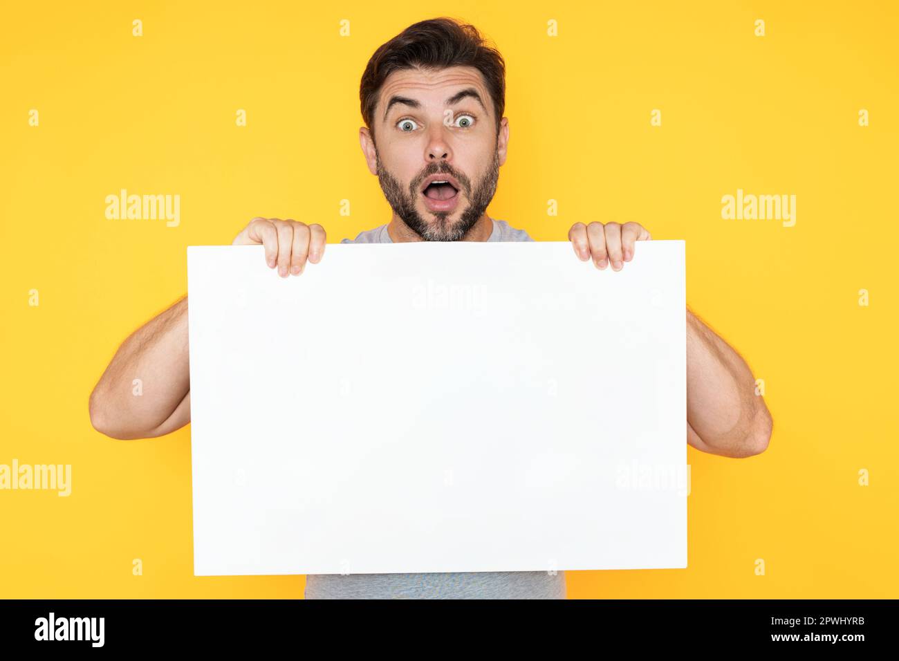 Amazed man showing promo blank board on studio background. Blank ...