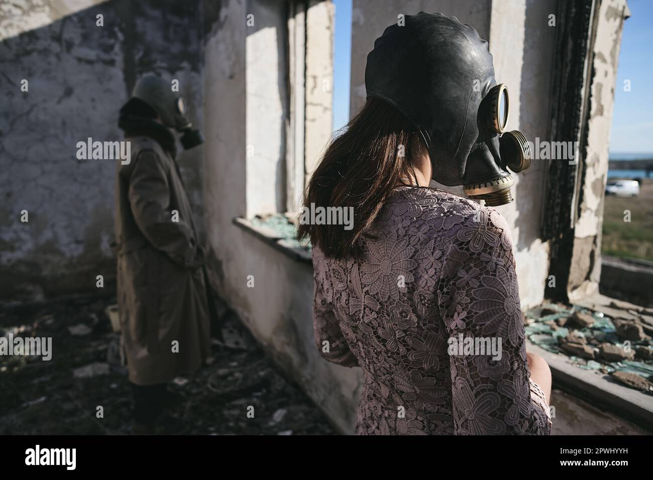 A woman and man in a gas mask stands in an abandoned building and looks ...