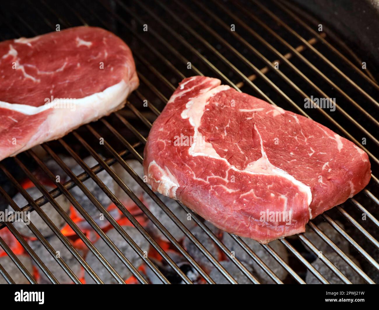 Raw Rib Eye Steak on grill grate over charcoal grill, preparing beef ...