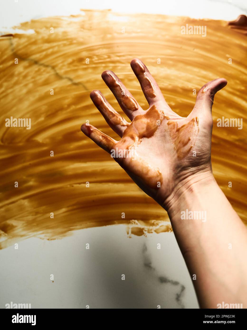 Salted Caramel sauce smeared on the tabletop. Hand and a tabletop ...