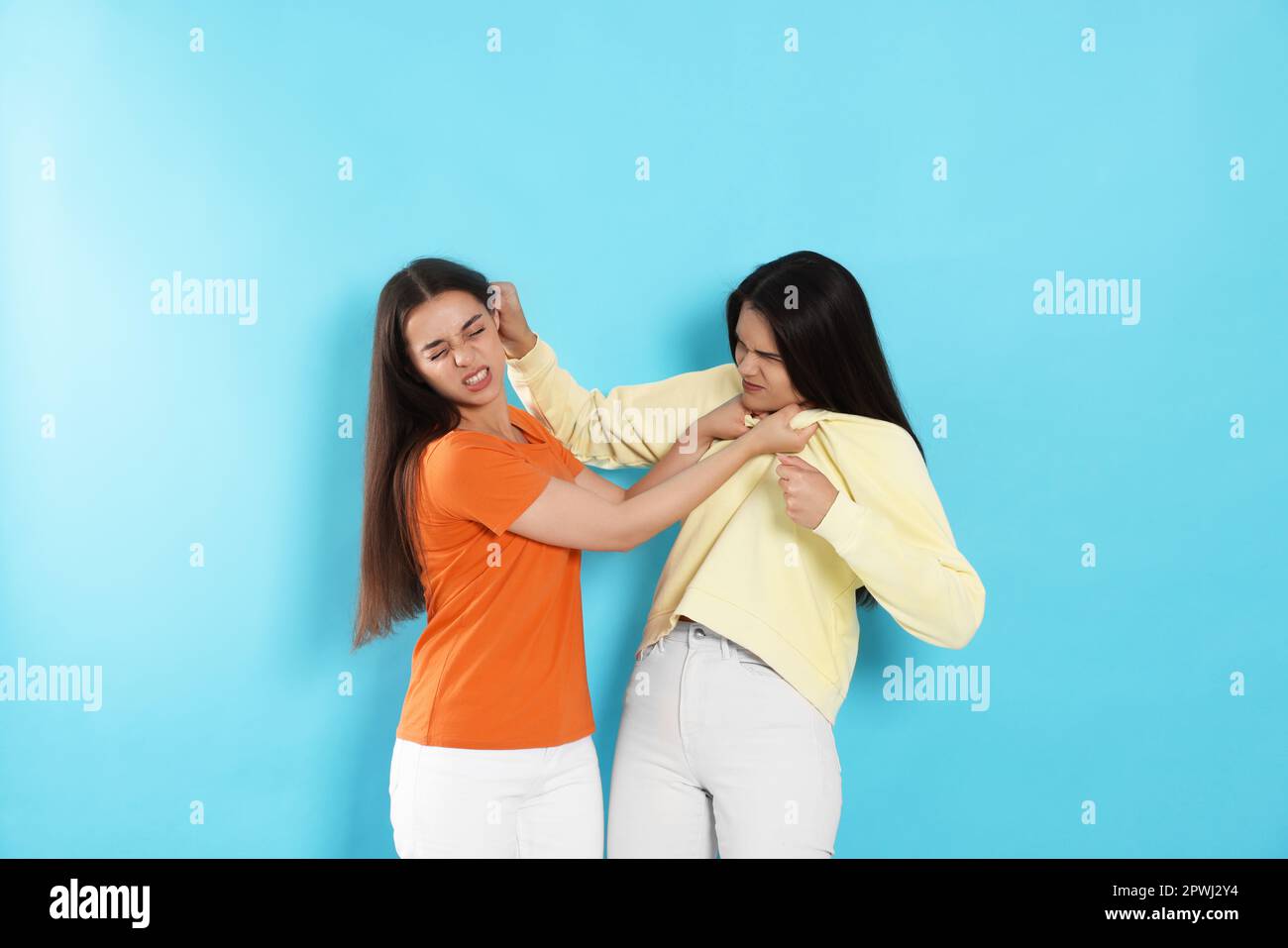 Aggressive young women fighting on light blue background Stock Photo ...