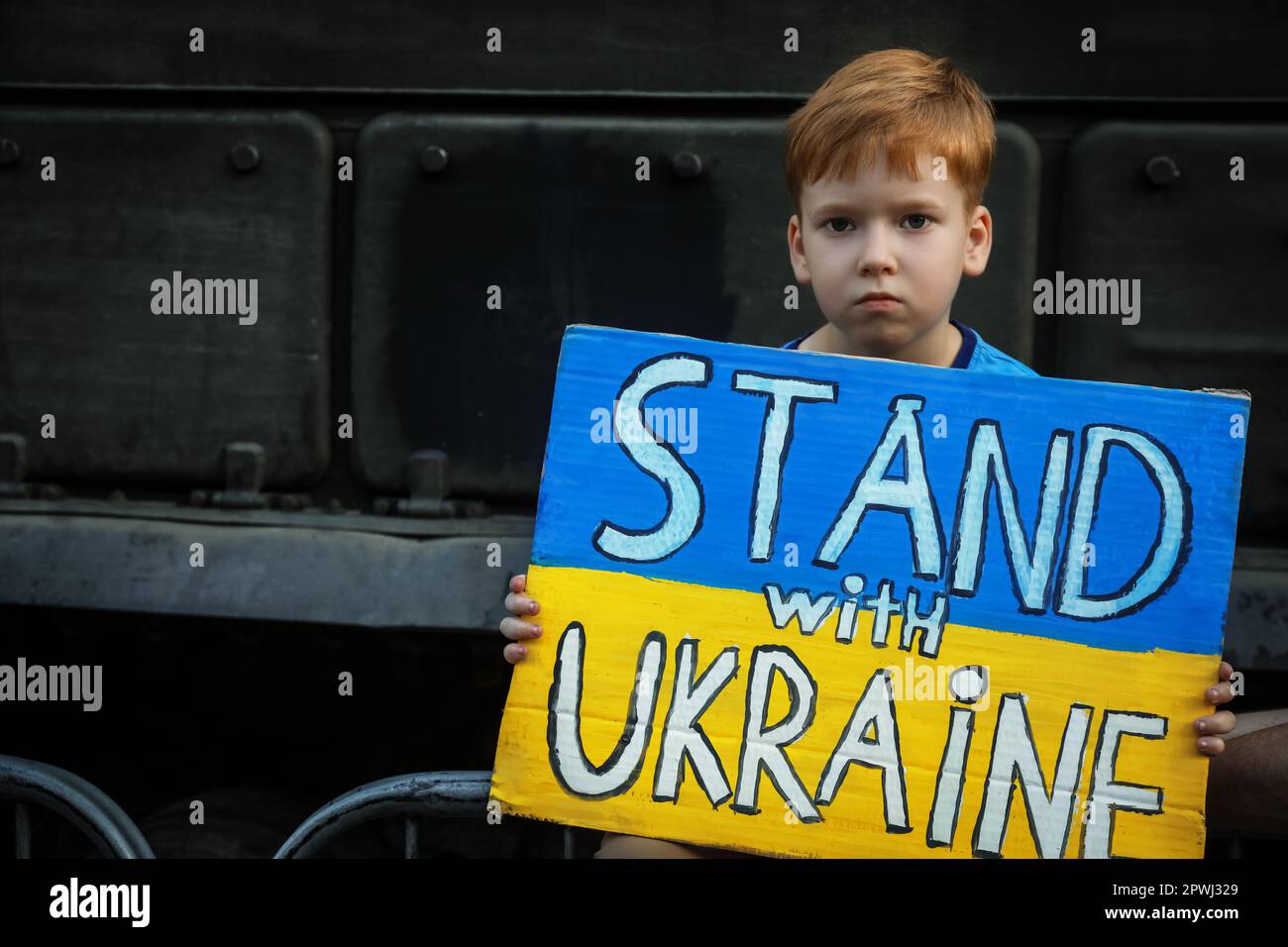 Sad boy holding poster in colors of national flag and words Stand With ...