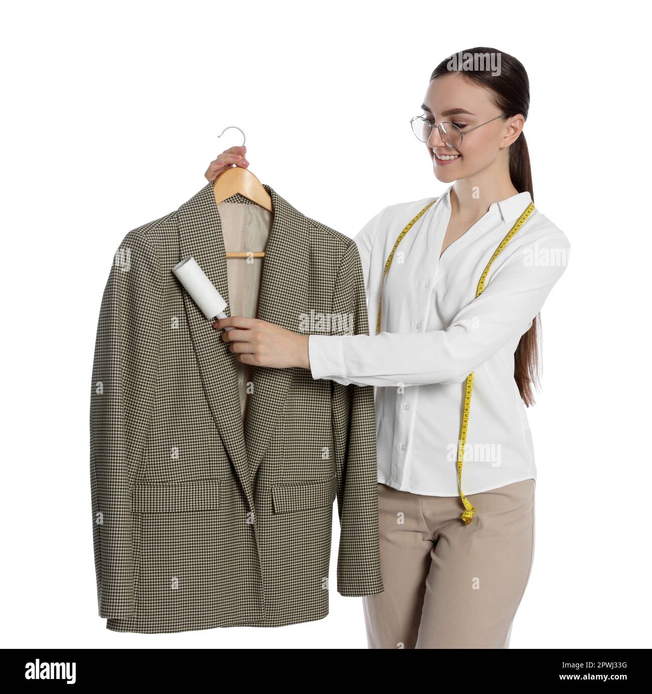 Young woman cleaning suit with lint roller on white background Stock ...