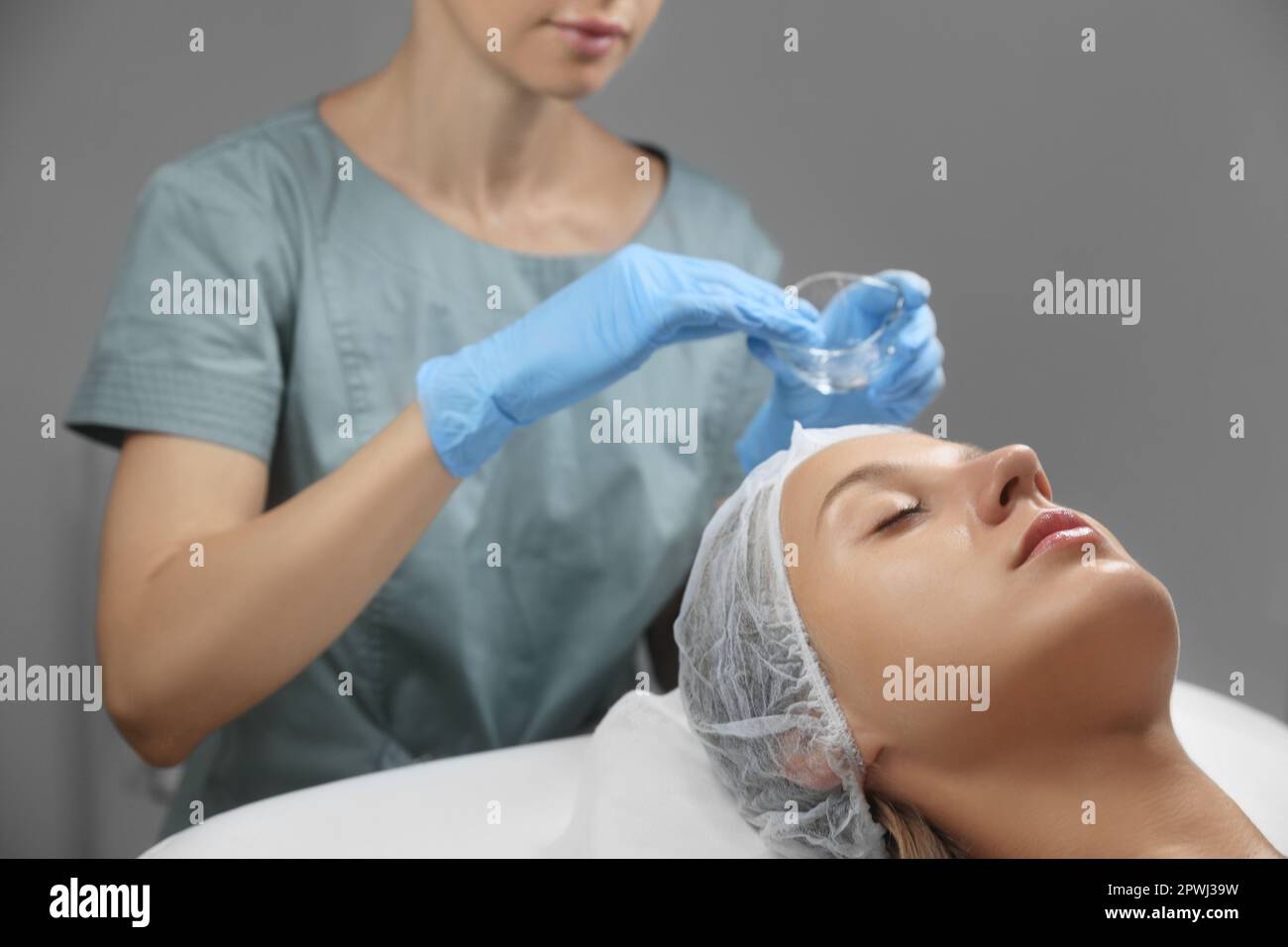 Cosmetologist applying chemical peel product on client's face in salon ...