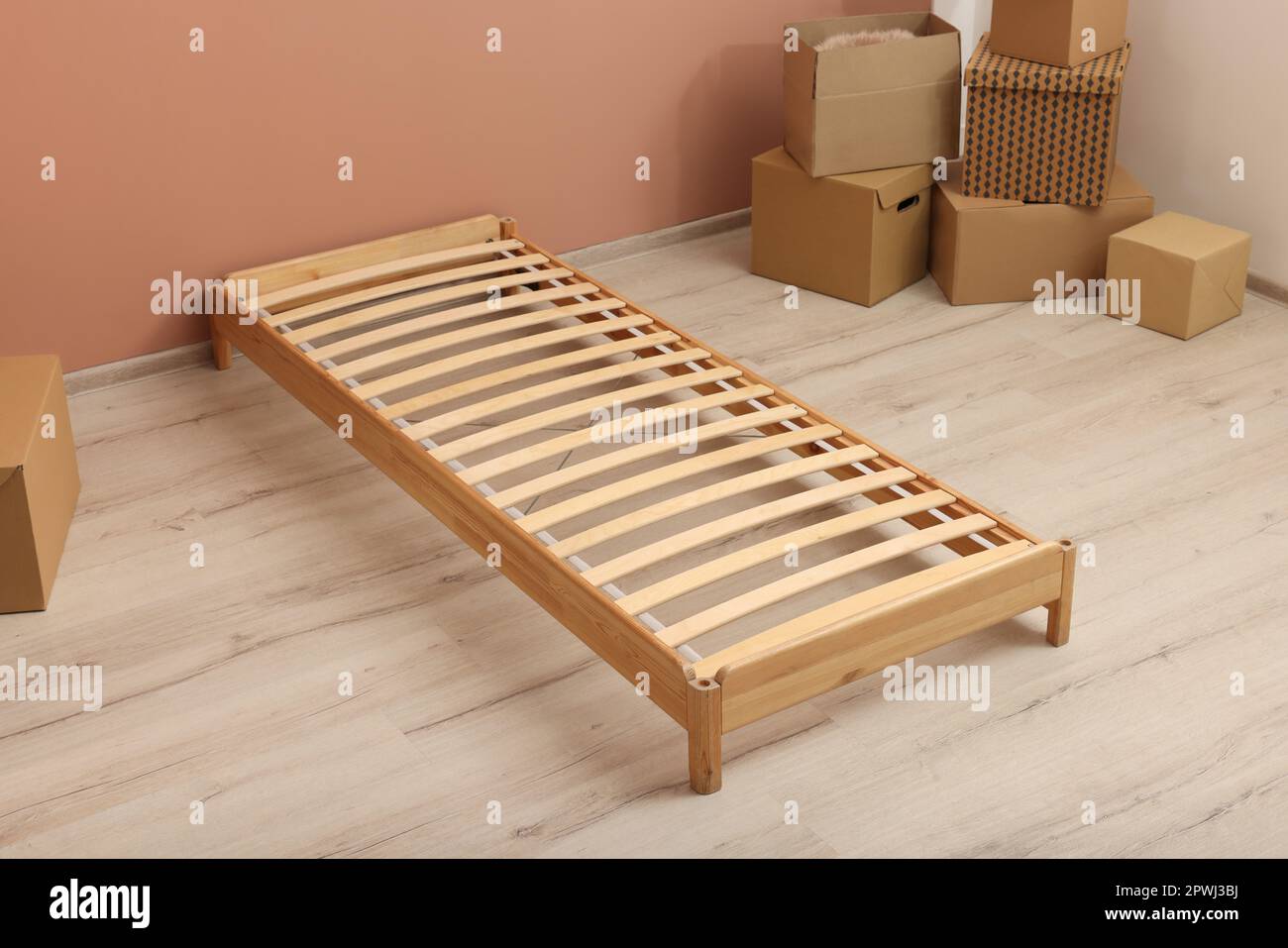Wooden bed frame and cardboard boxes on floor in room Stock Photo - Alamy