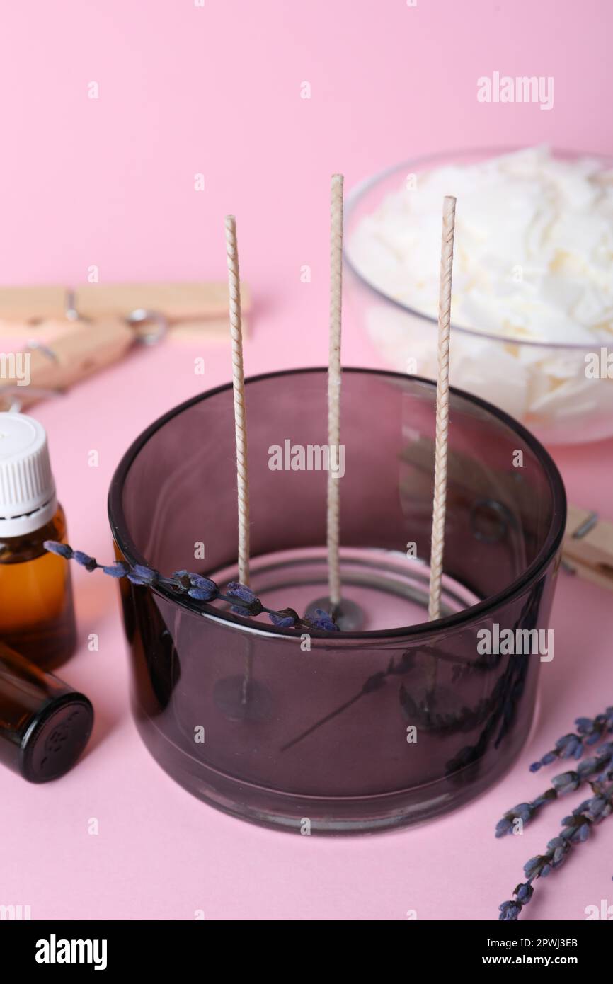 Container with wicks and lavender flowers on pink background. Making ...