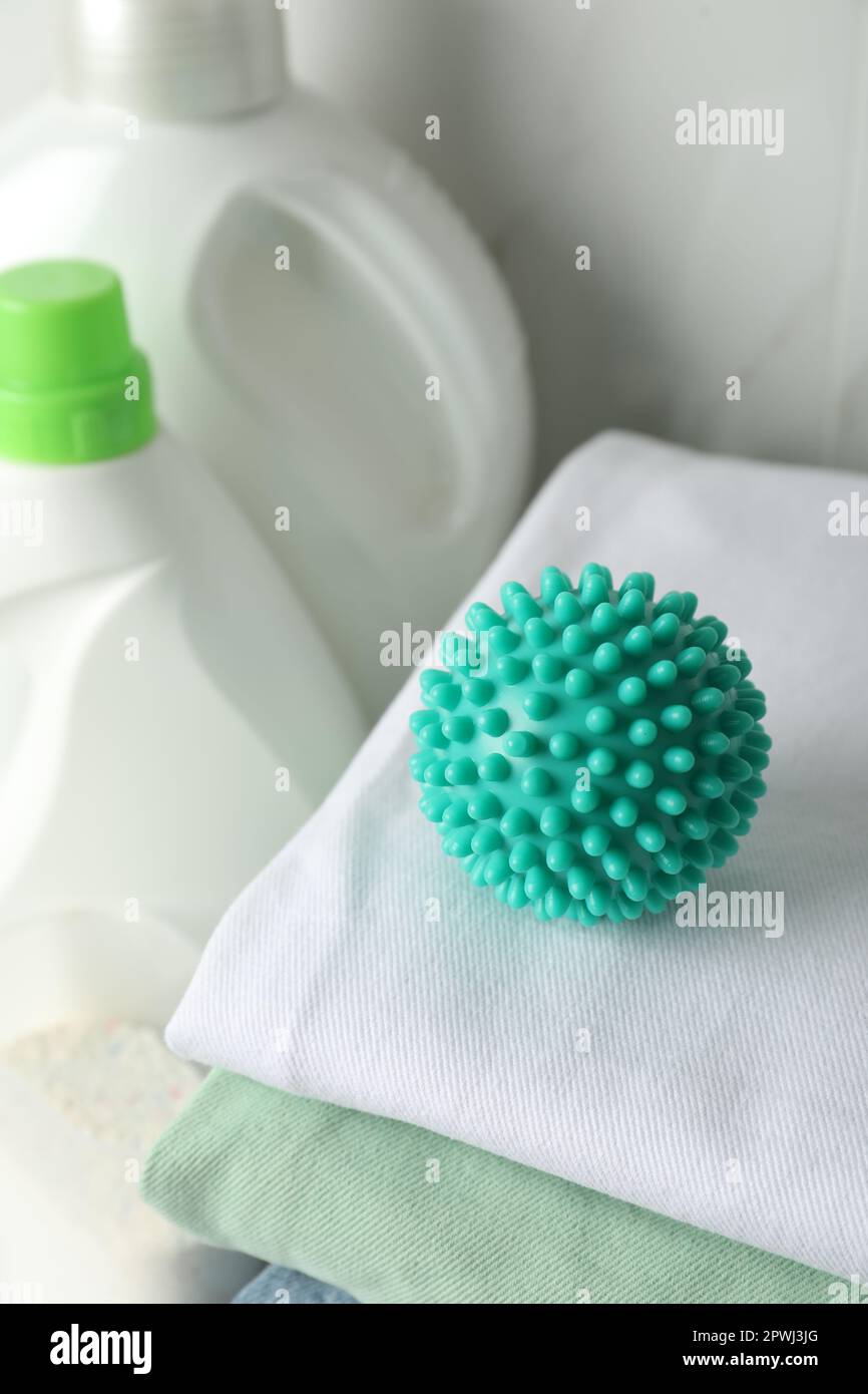 Turquoise dryer ball on stacked clean towels near laundry detergents ...