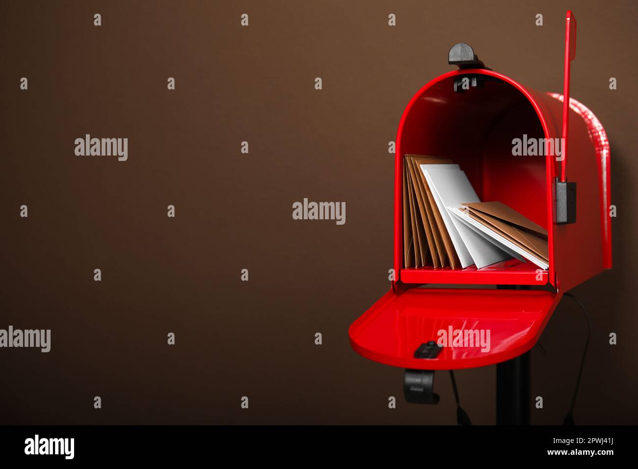 Open red letter box with envelopes against brown background. Space for ...