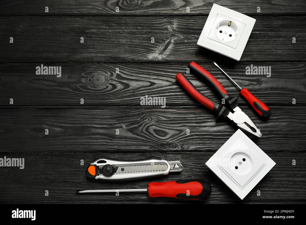 Set of electrician's tools and power sockets on black wooden table ...