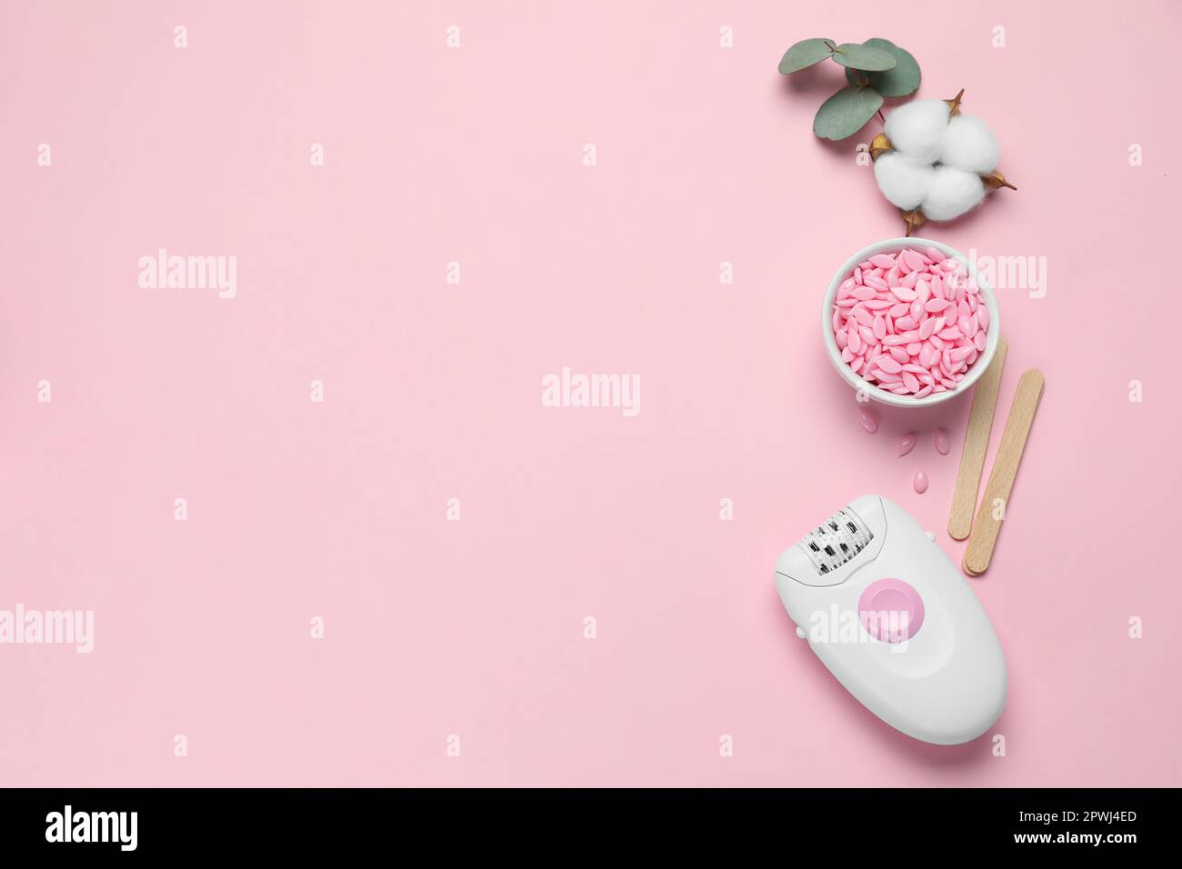 Modern epilator, depilatory wax and fluffy cotton flower on pink ...