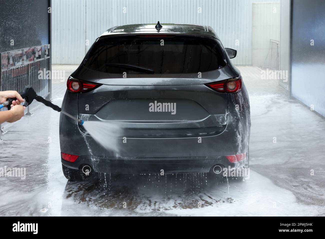 Man washing auto with high pressure water jet at car wash, closeup ...