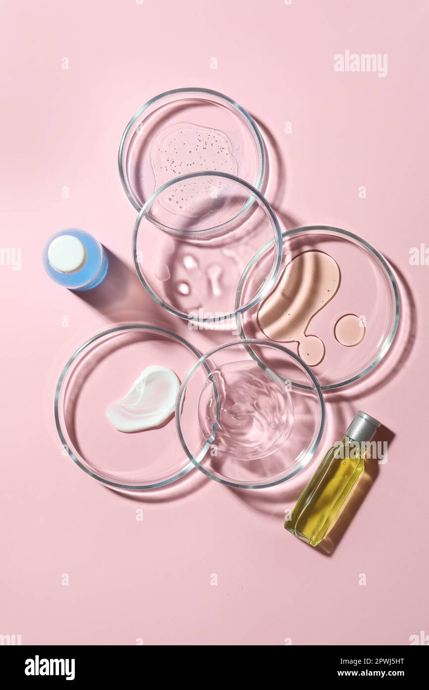 Many Petri dishes and cosmetic products on pink background, flat lay ...
