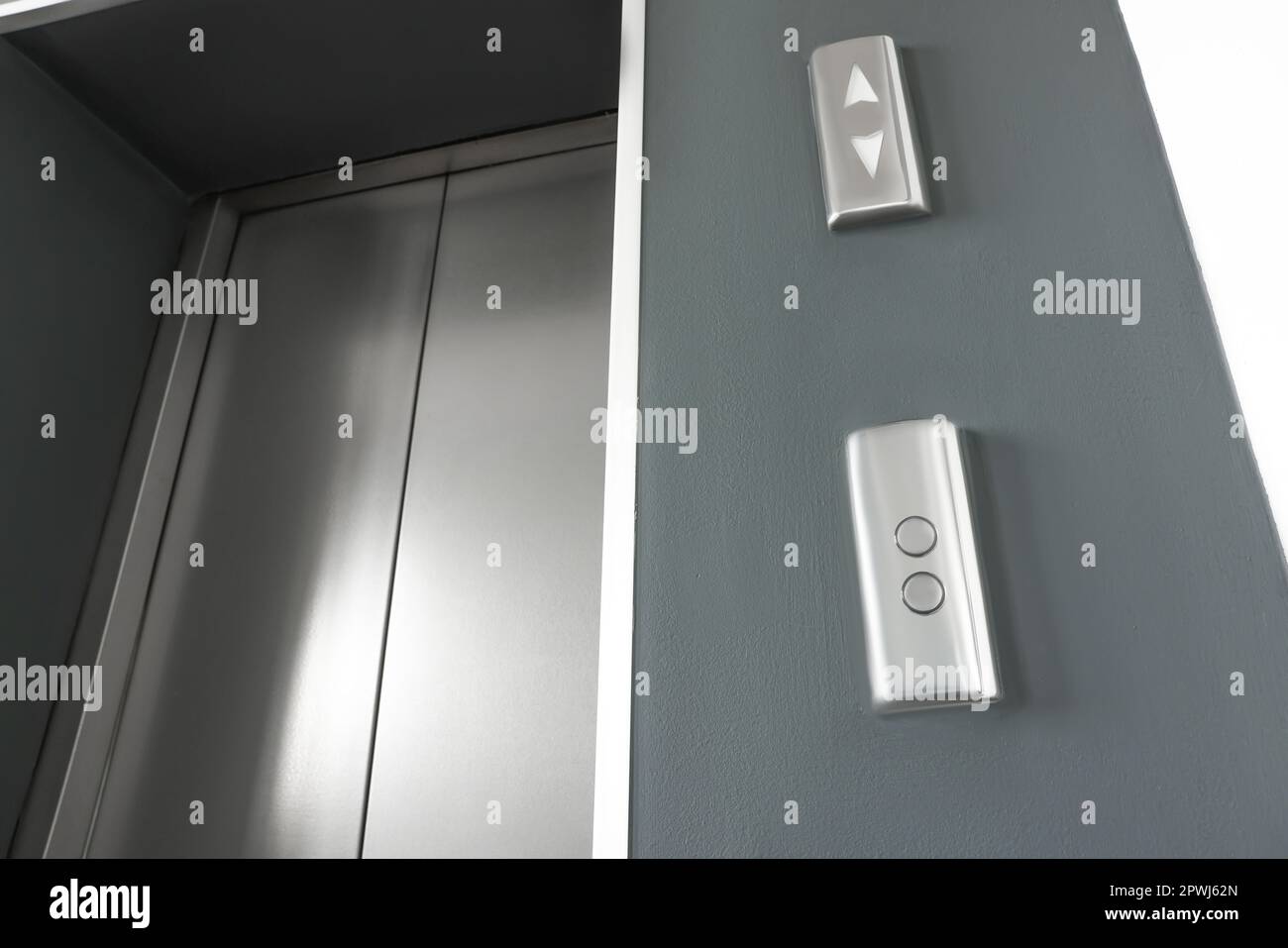 Elevator call buttons on grey wall near door Stock Photo - Alamy
