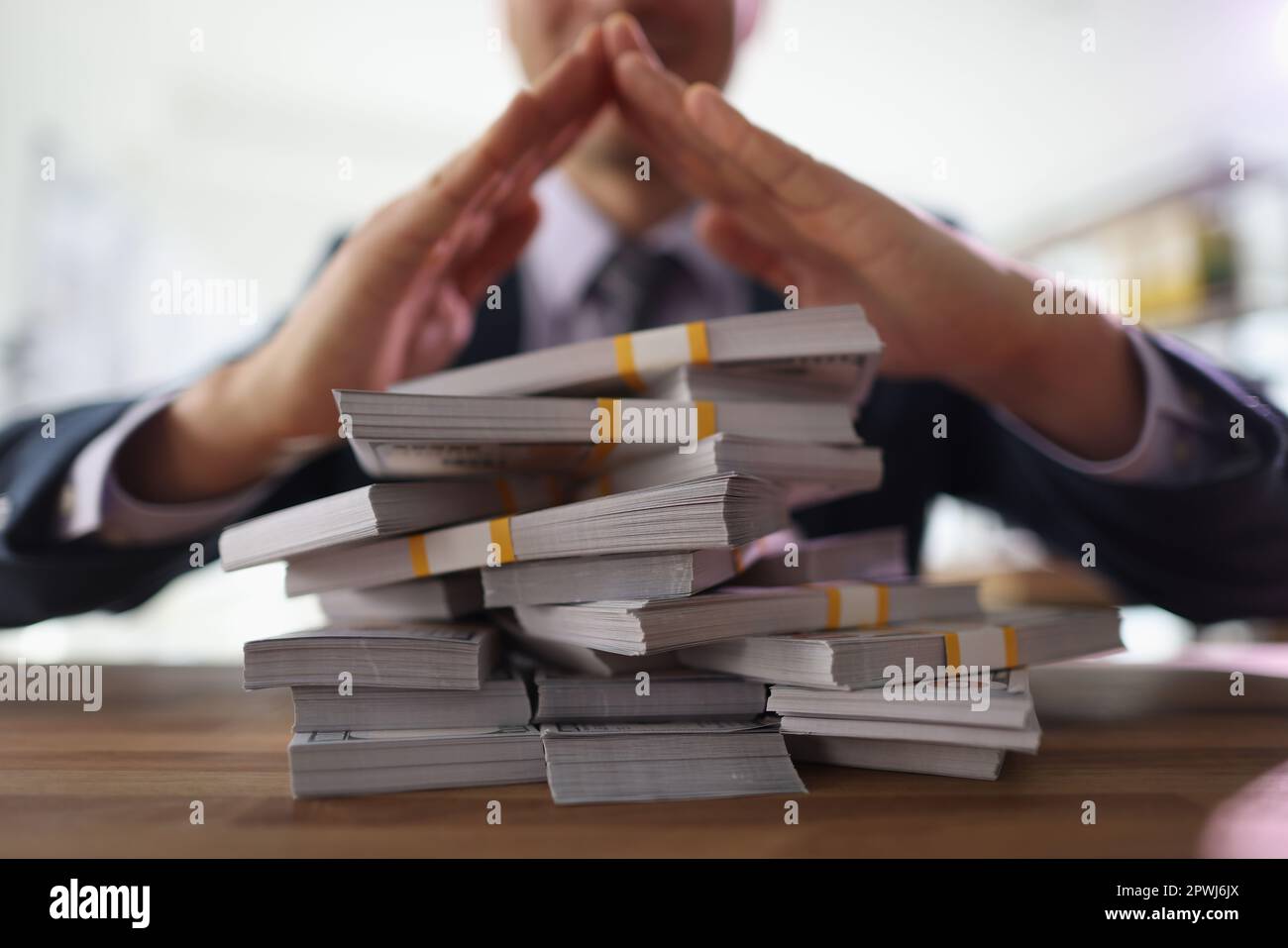 Businessman makes pyramid with hands above stacks of money Stock Photo ...