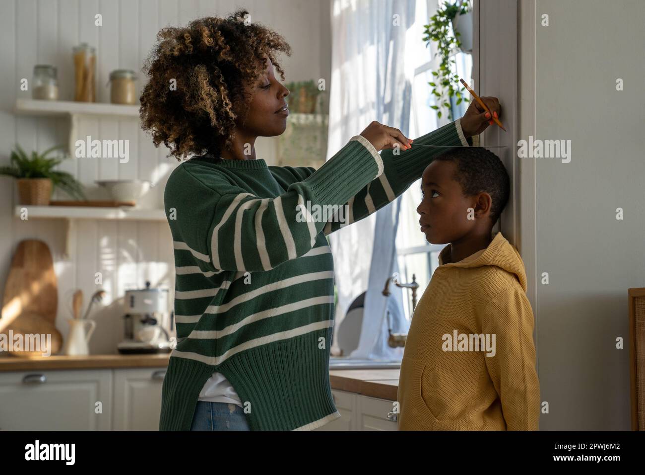 Loving black woman tracking increase measures changes height of kid son ...