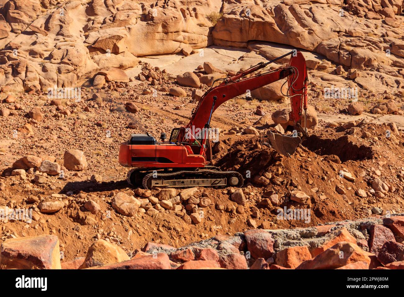 Orange excavator working at construction site in desert in Sinai ...