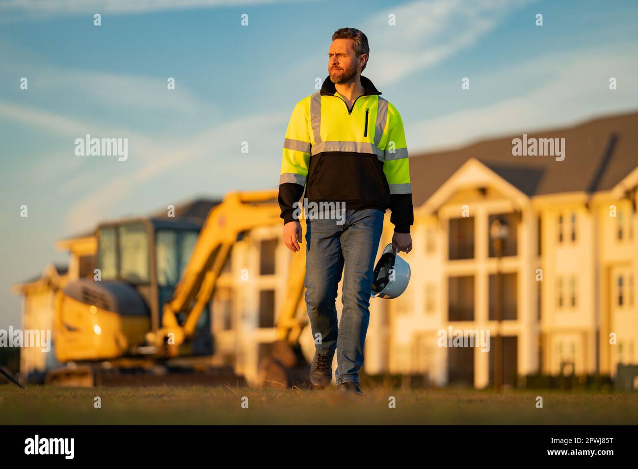 Builder in a construction site. Builder with excavator ready to build ...