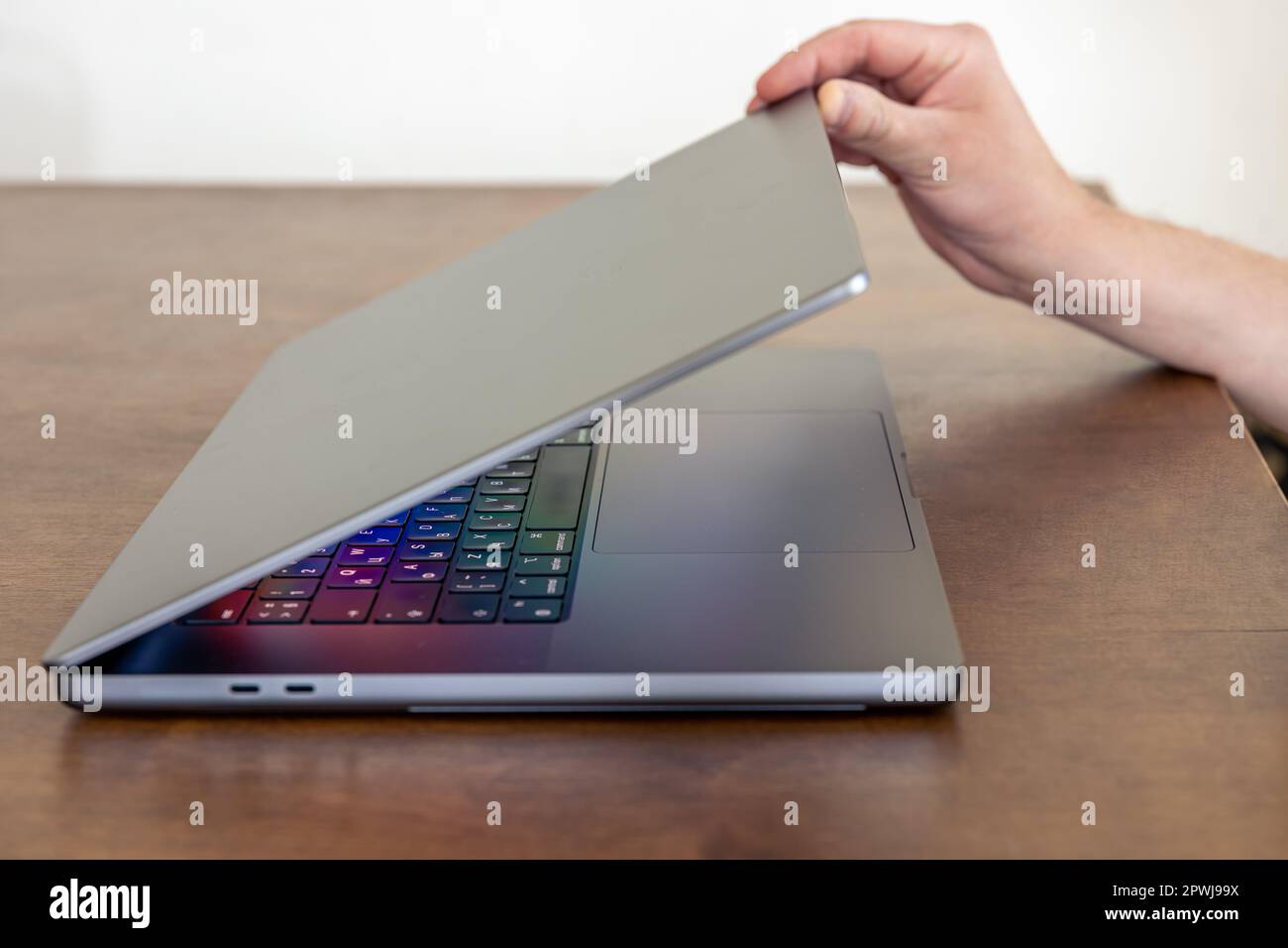 A man's hand opens a laptop with a multi-colored glowing screen Stock ...
