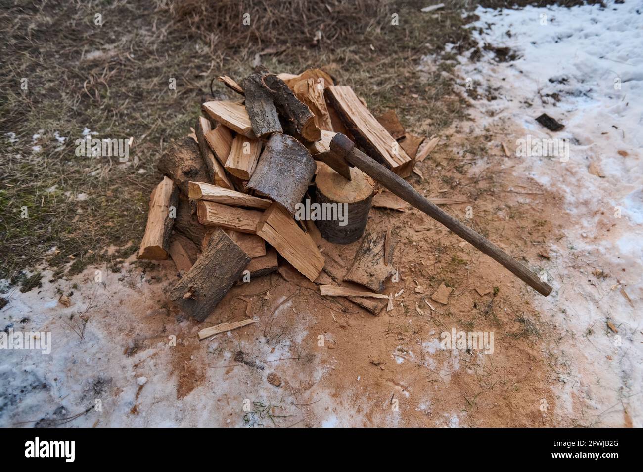 Top view hatchet or wood-burning axe sticking in a stump near a heap of ...