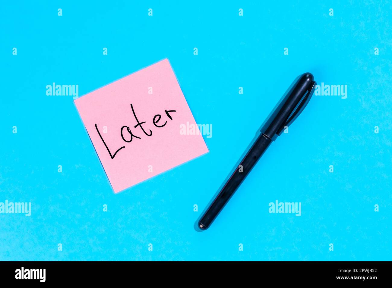 Pink note with with inscription Later and marker on blue background ...