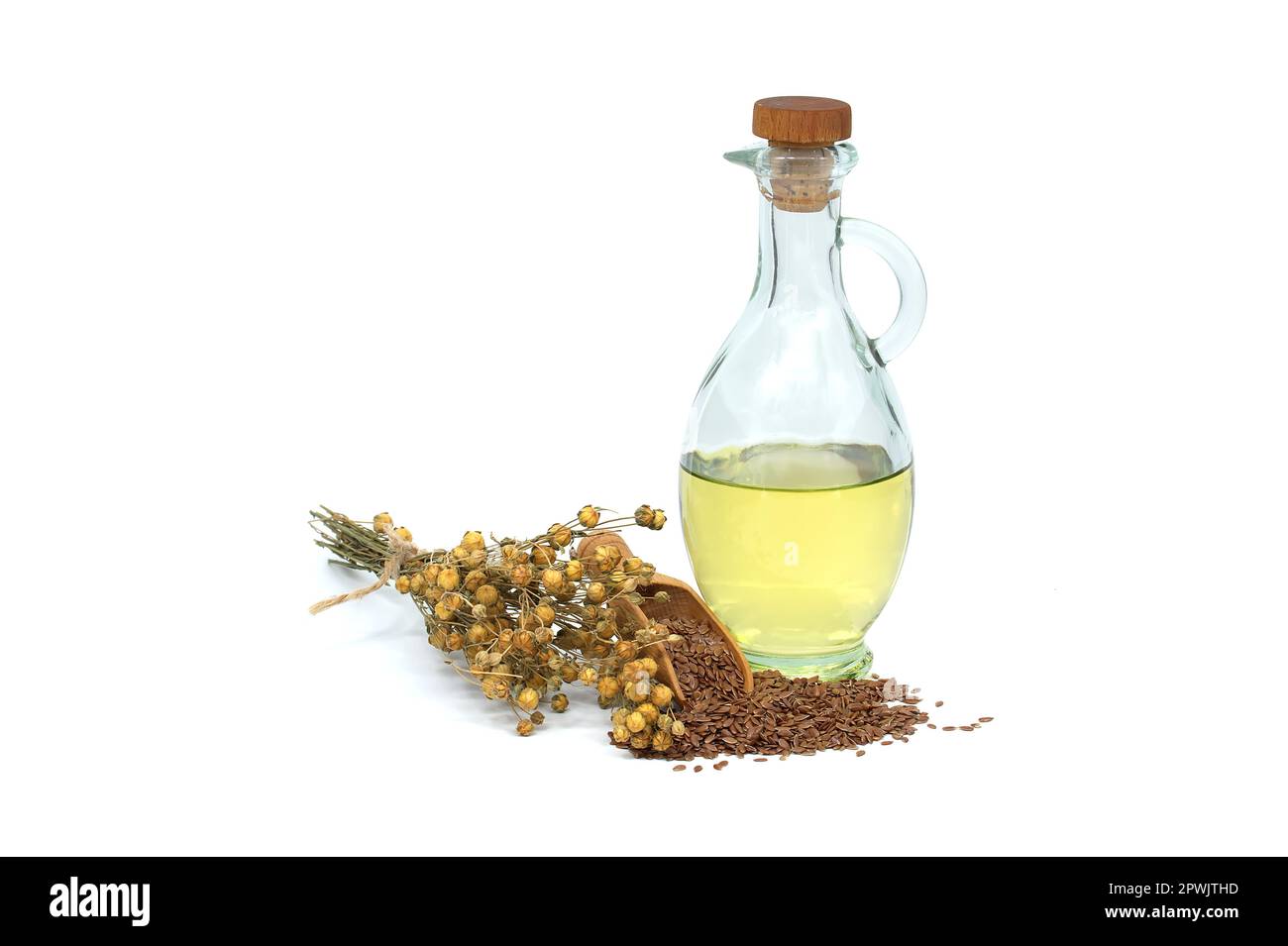 Linseed oil in glass decanter and flax seeds in wooden scoop and bunch of flax plants isolated ...