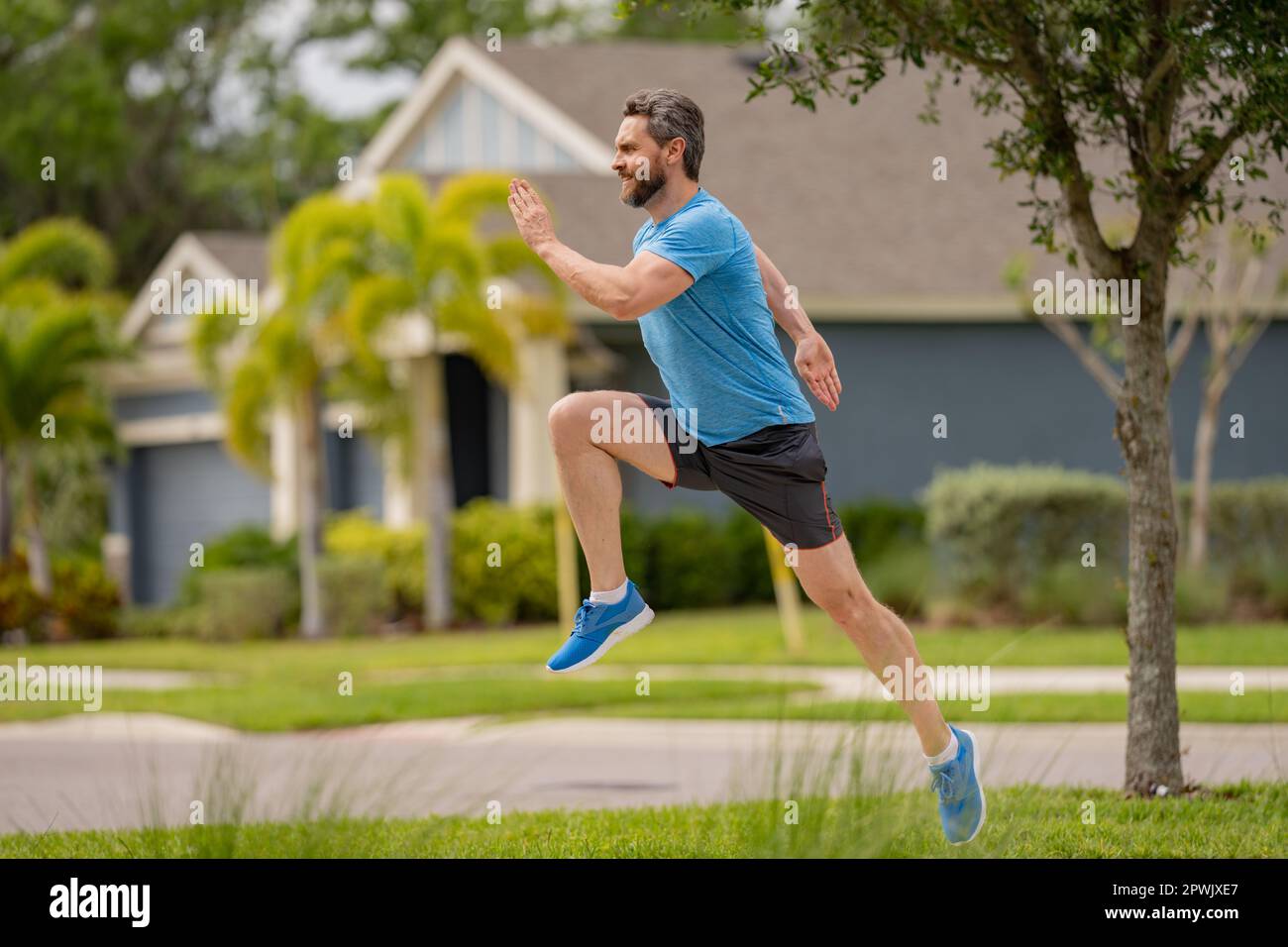 Handsome middle aged man running across american neighborhood. Athletic ...