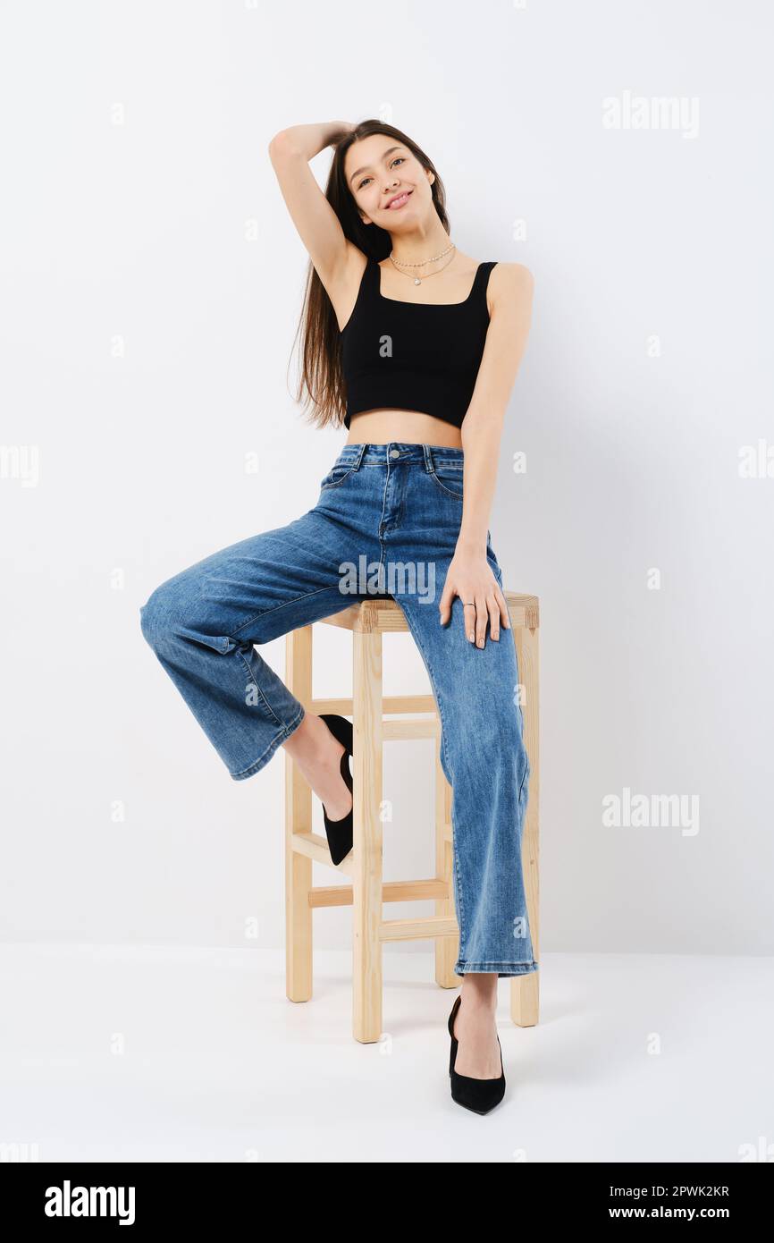 Full length portrait of smiling young woman in black tank top and wide ...