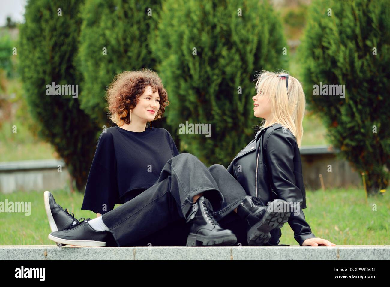 Two young best friends sitting next to each other in the park Stock ...