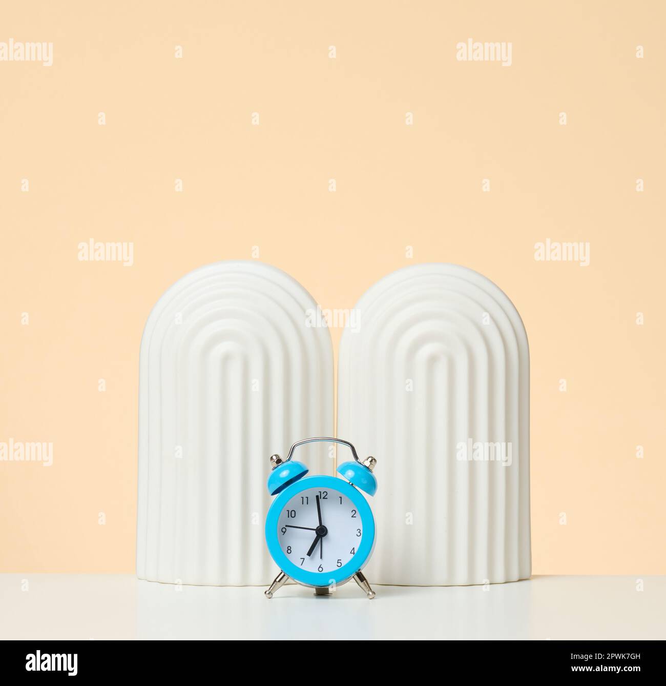 Round alarm clock on a white table. The time is seven in the morning ...