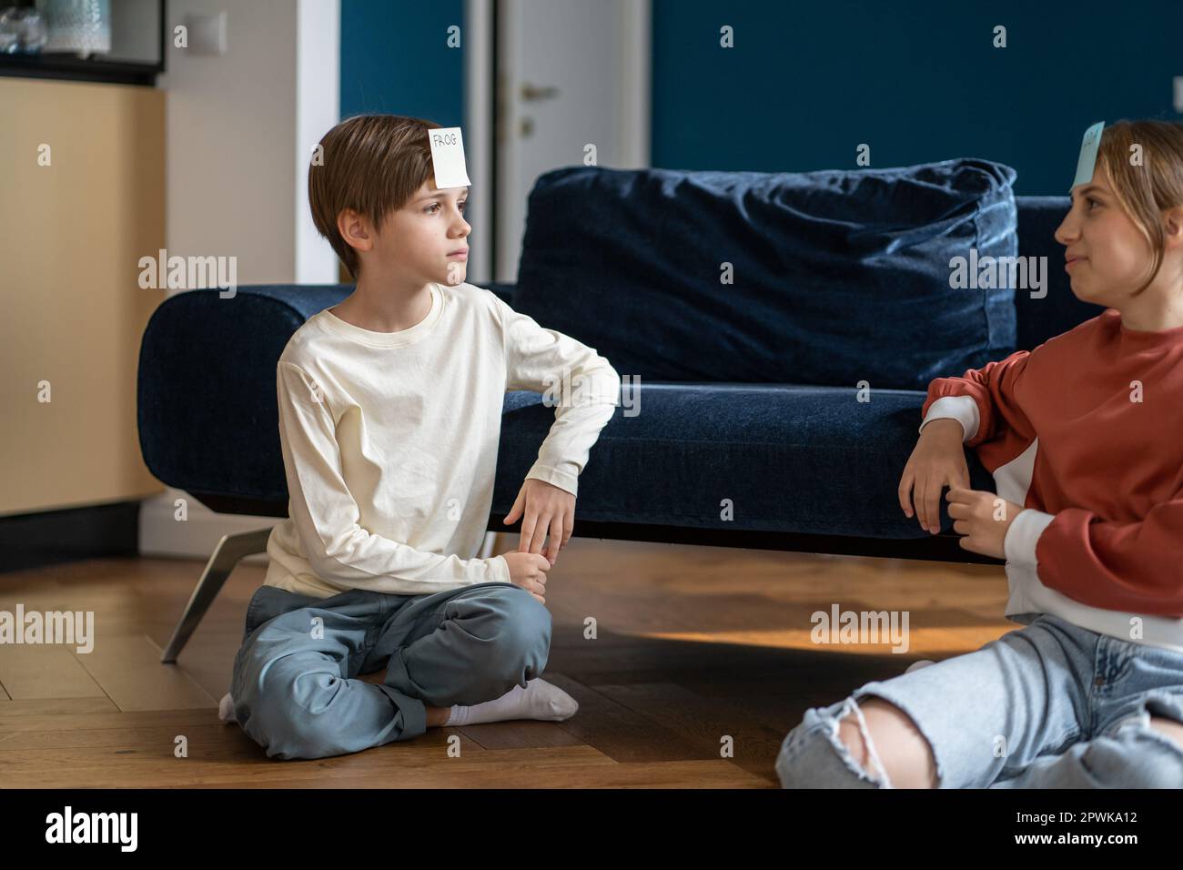 Small children boy and girl playing guessing game with sticky notes ...