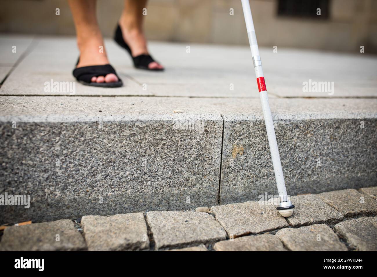 Blind woman walking on city streets, using her white cane to navigate ...