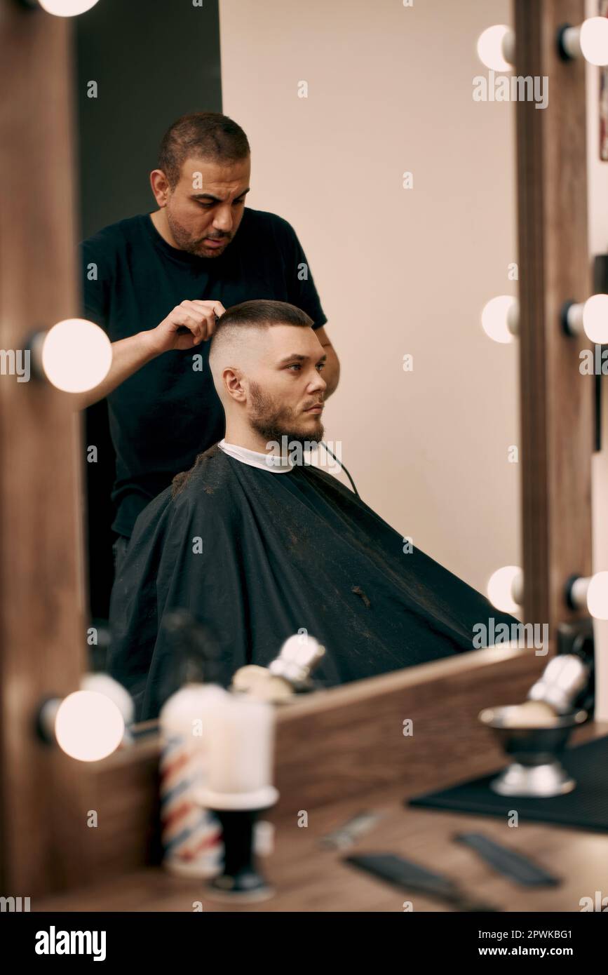 master hairdresser does hairstyle with scissors and comb Stock Photo ...