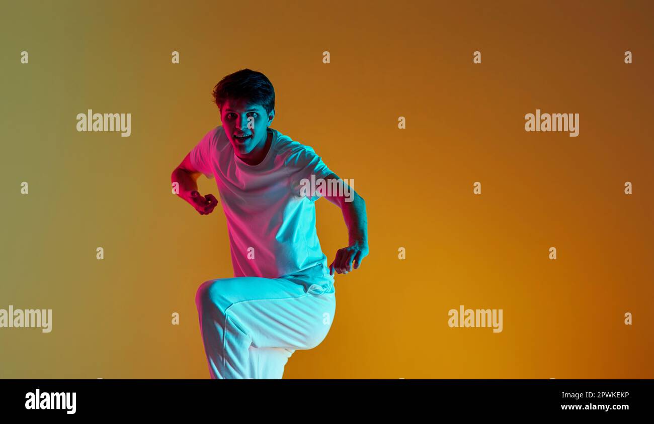 positive sportive man dancing on yellow background. Neon lighting Stock ...