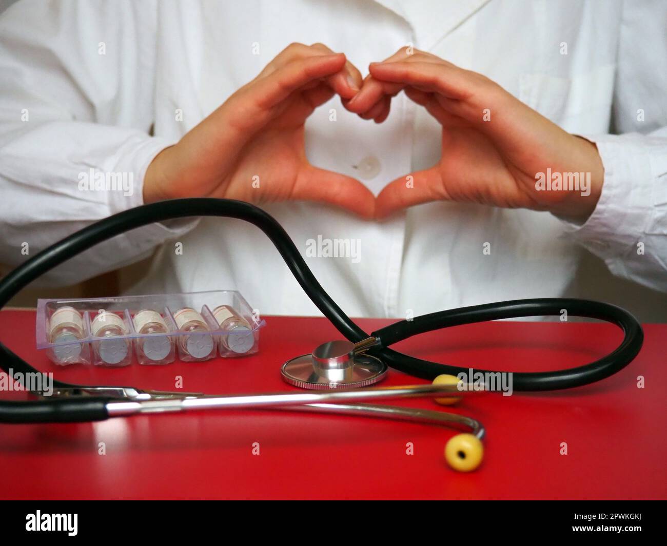 Doctor cardiologist with a stethoscope shows the heart with his hands ...