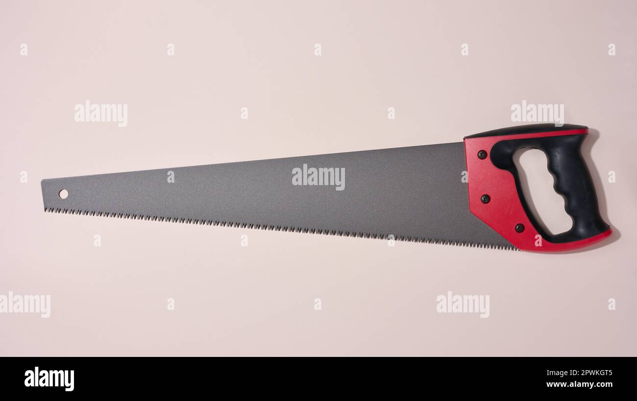New hand saw with a rubber red handle on a beige background, top view ...