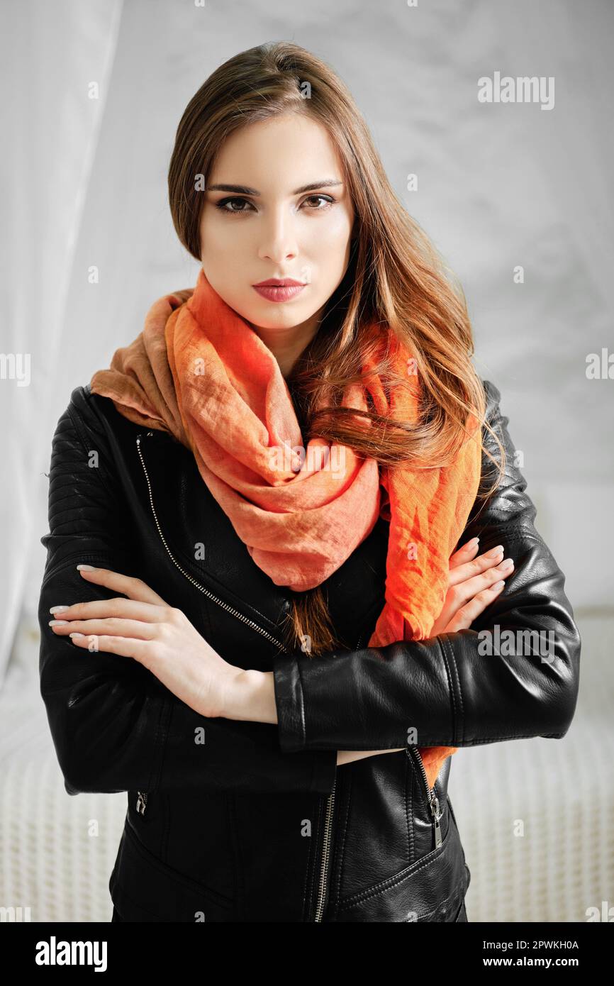 Trendy woman in leather jacket and silk scarf over her neck standing ...
