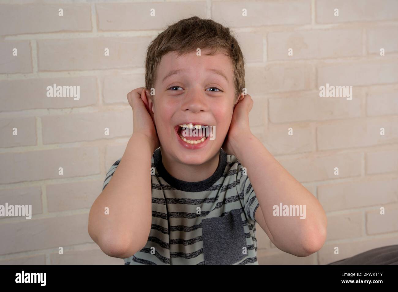 boy covers his ears with his hands and laughs Stock Photo - Alamy