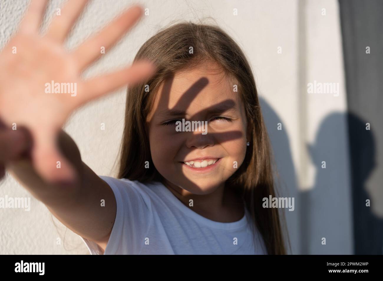 girl covering her face from the bright sun while standing against the ...