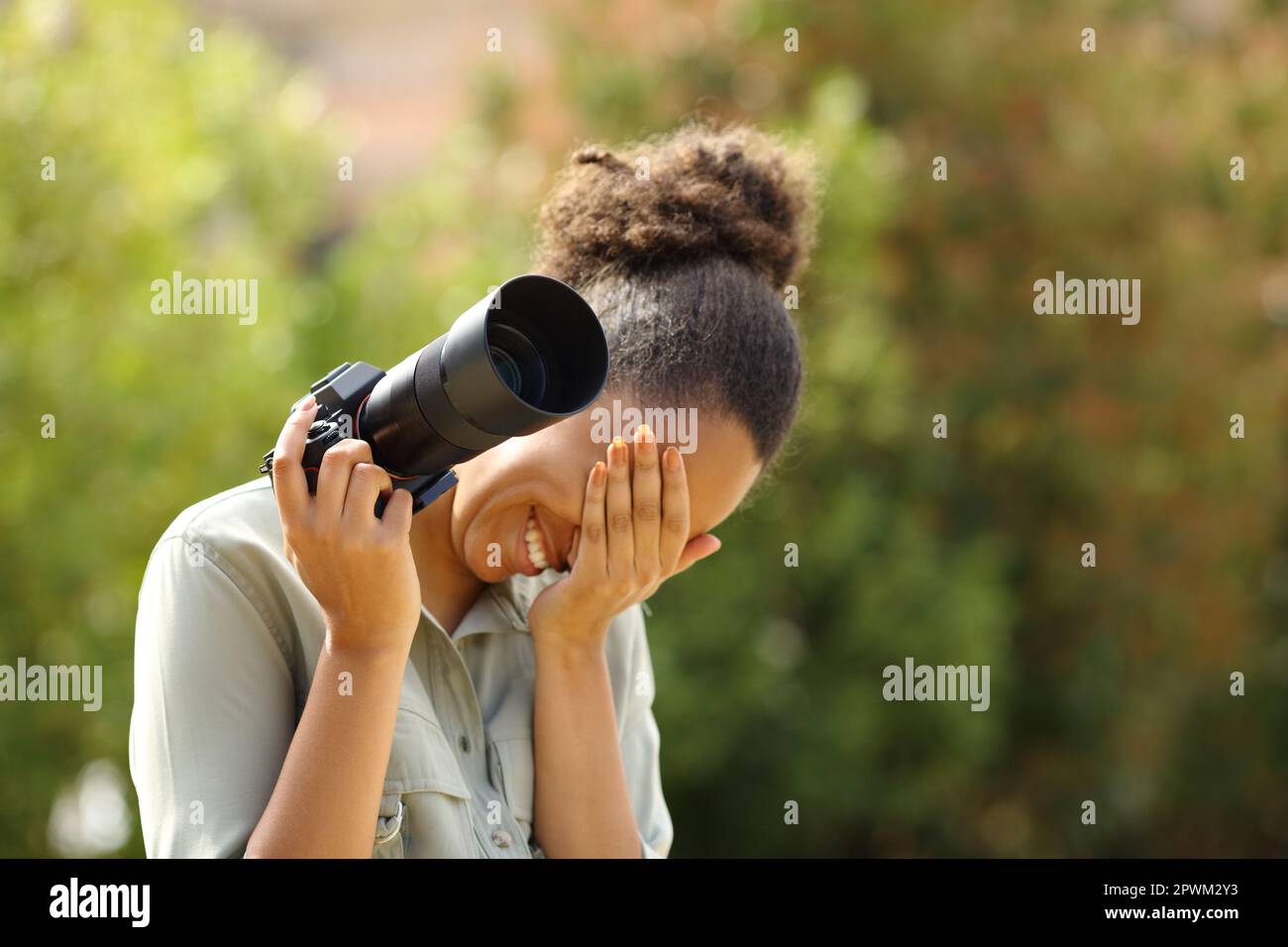 Embarrassed black photographer laughing and hiding face holding ...