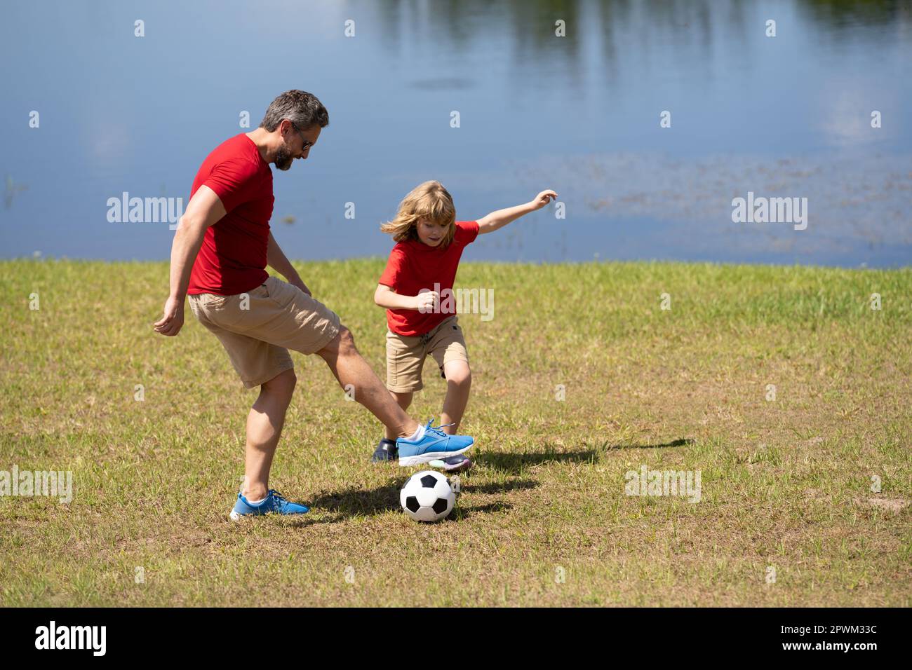 Dad and son playing football together on green meadow. Father and son ...
