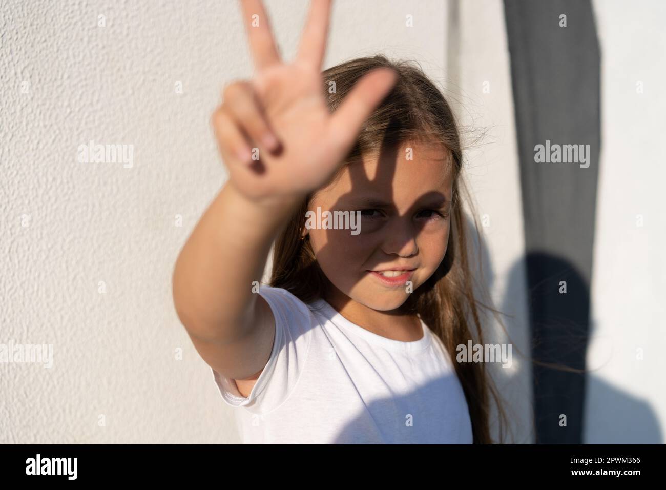 girl covering her face from the bright sun while standing against the ...