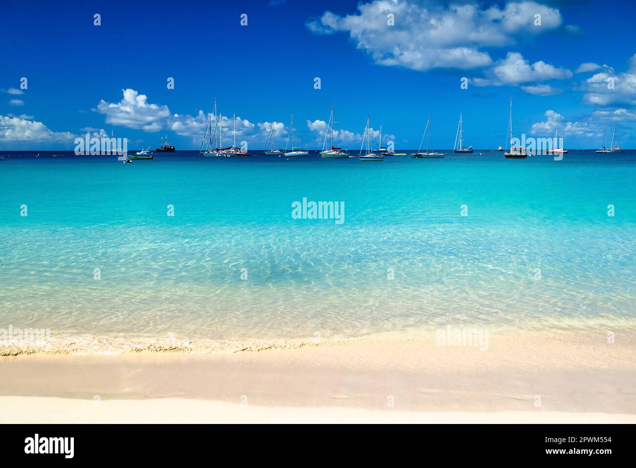 A view of the dream beach in Barbados with a blue sky and sailing boats ...