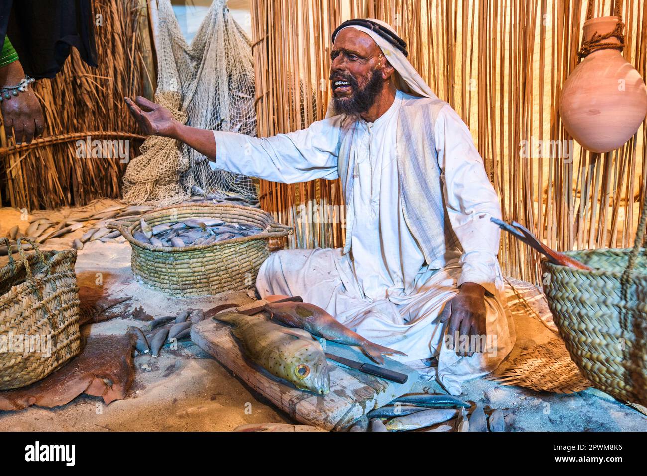 An old merchant selling fish, seafood to a woman wearing a black burka ...