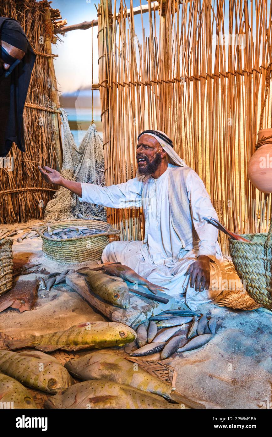 An old merchant selling fish, seafood to a woman wearing a black burka ...