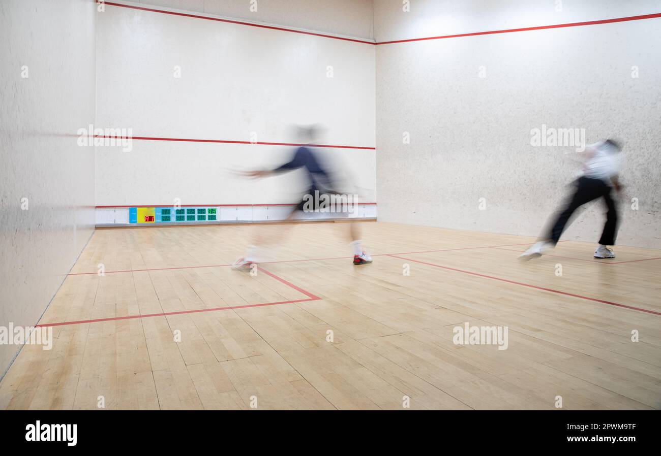 Squash players in action on a squash court (motion blurred image; color ...