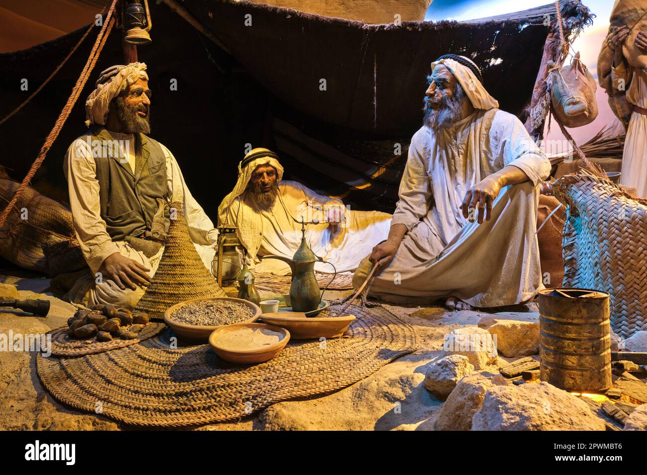 A group of tribesmen eating in front of a campfire and tent in the ...