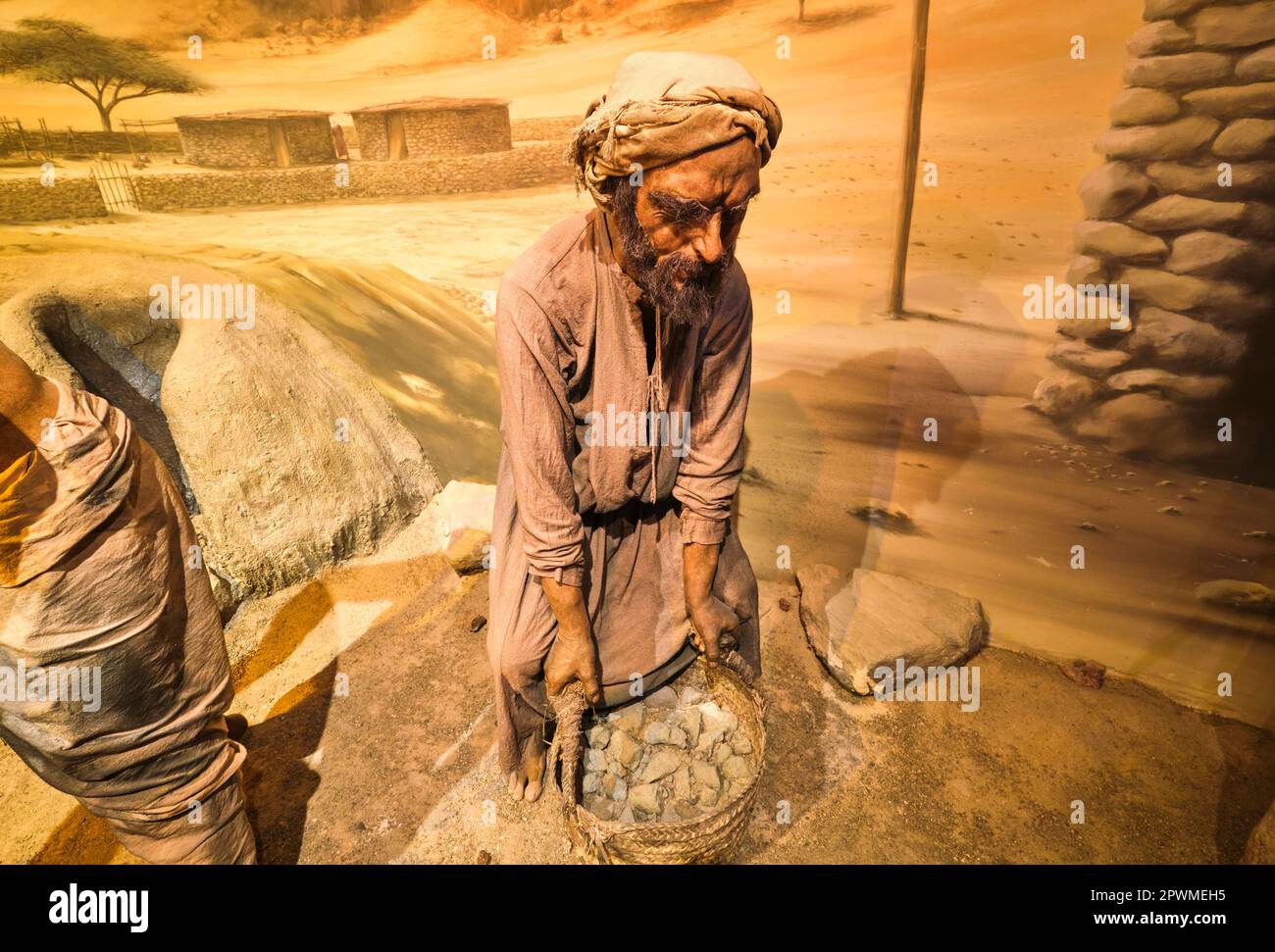 A bearded worker, miner, hauling a heavy basket of rocks. A diorama ...