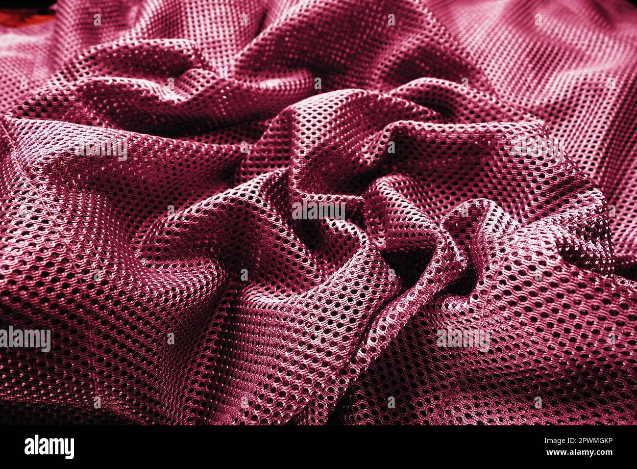 Synthetic fabric with holes, laid in waves and twisted into folds ...
